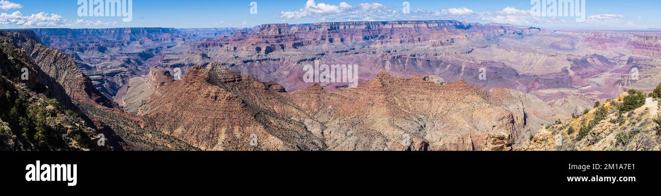 A panorama of the Grand Canyon in late morning sun with a blue, nearly ...