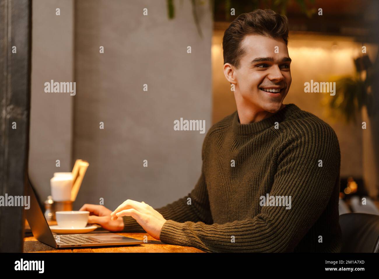 Young white man wearing sweater smiling and looking backward while ...