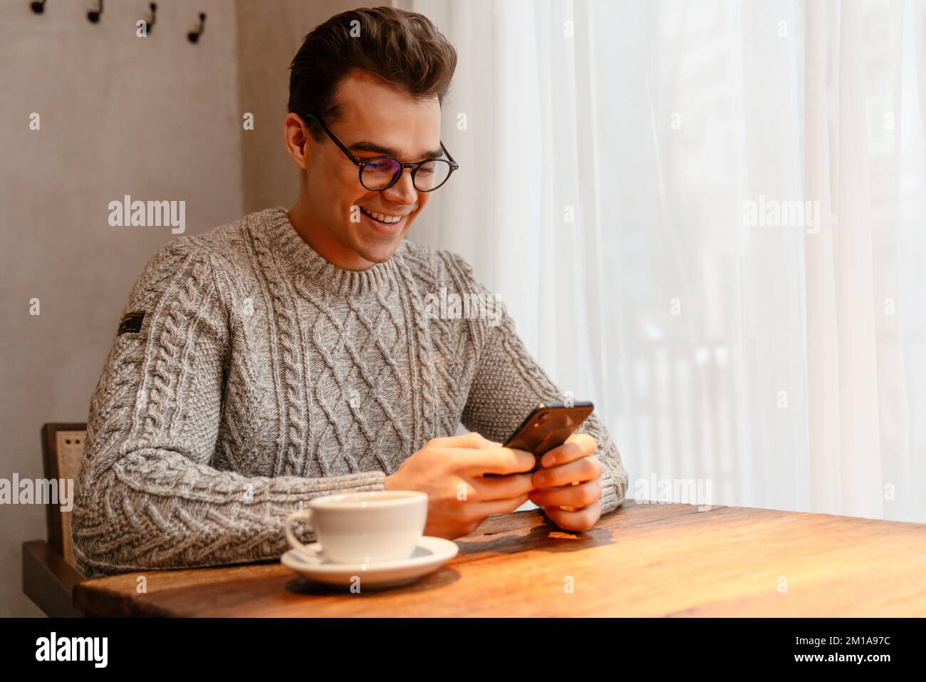 Young white man wearing eyeglasses smiling while drinking coffee and ...