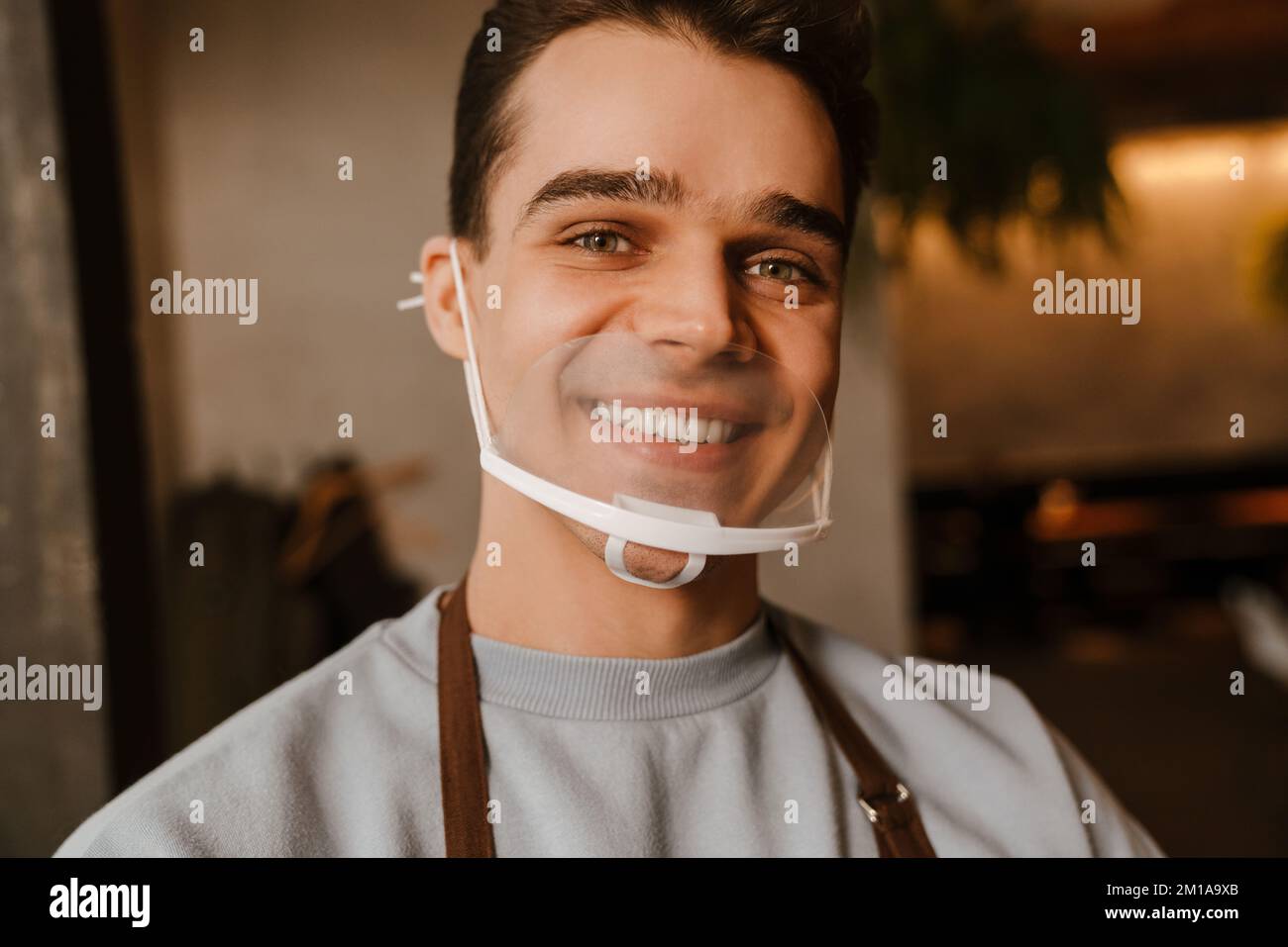 Young white waiter man wearing apron and face mask smiling while ...