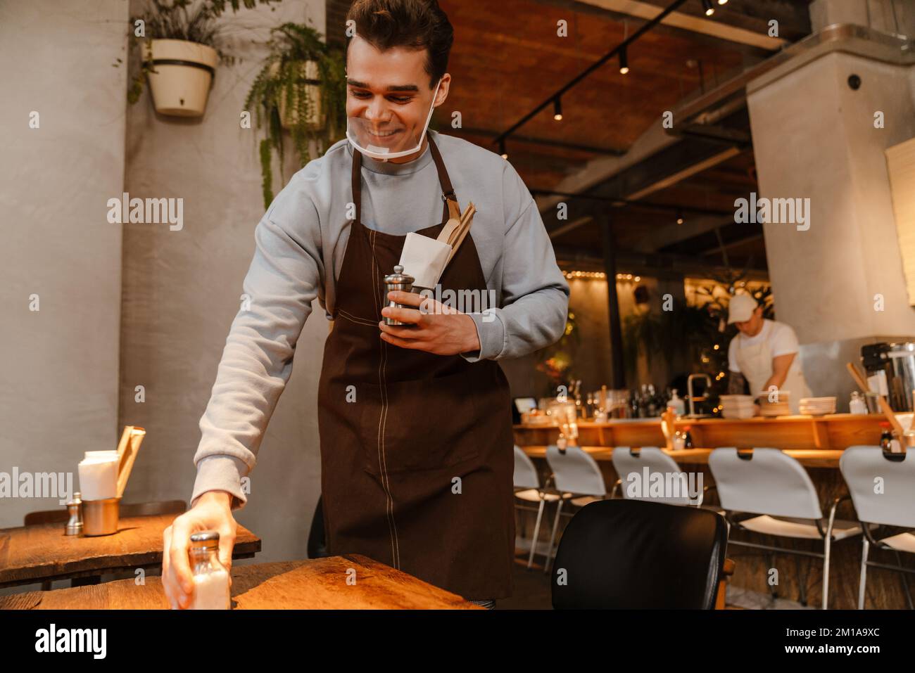 Young white waiter man wearing apron and face mask smiling while ...