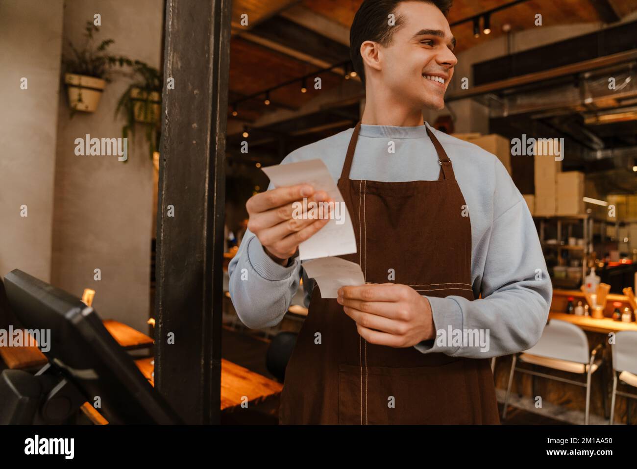 Young white waiter man wearing apron standing in front of computer and ...