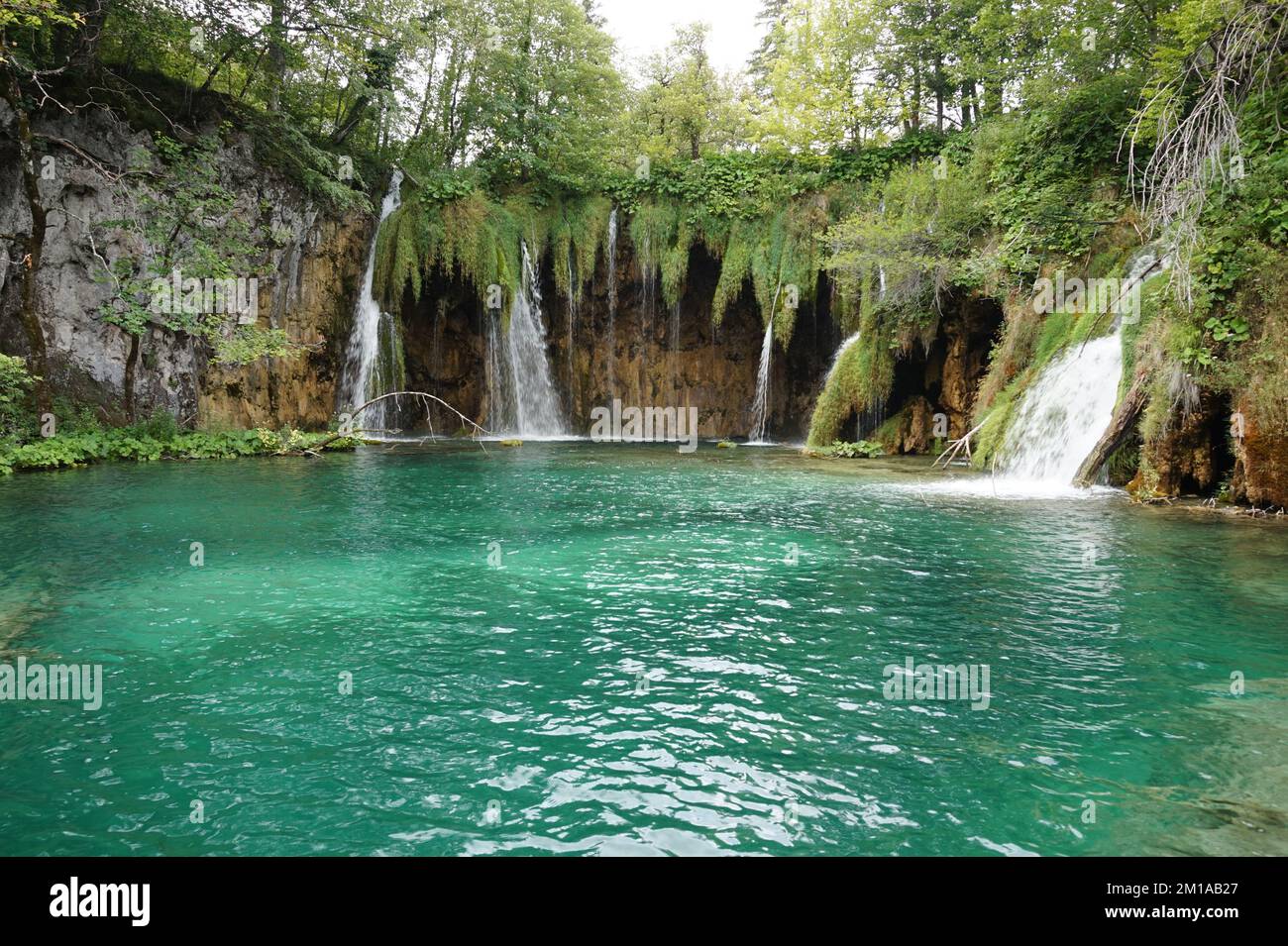 Multiple waterfalls flowing into a blue lake at Plitvice Lakes National ...