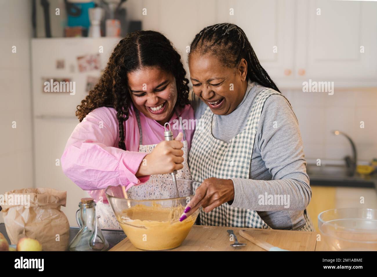 Happy African mother and daughter having fun preparing a homemade ...