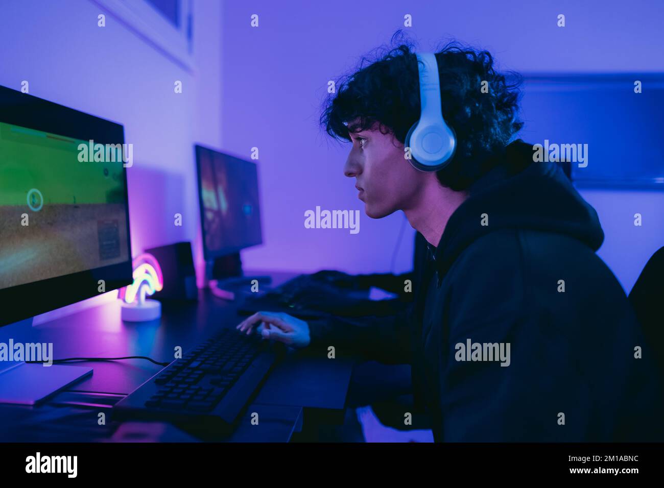 Young gamer having fun playing online video games with computer at home ...