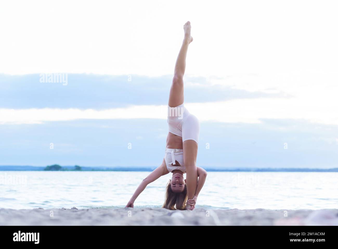 Young woman doing complex Yoga exercise headstand with Namaste asana ...