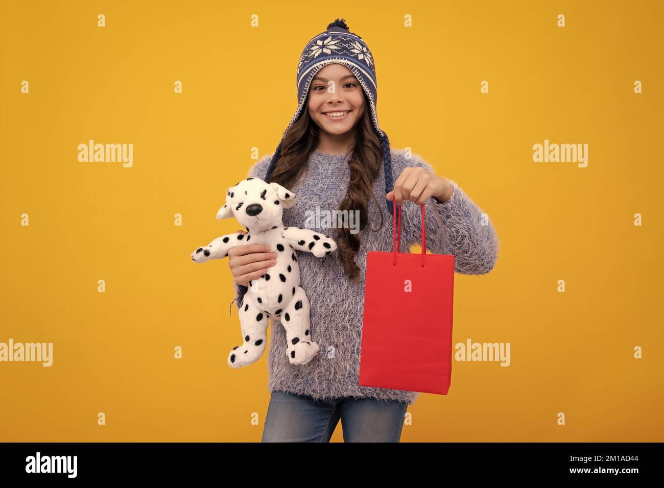 Teenager child girl in winter hat with shopping bags on yellow ...