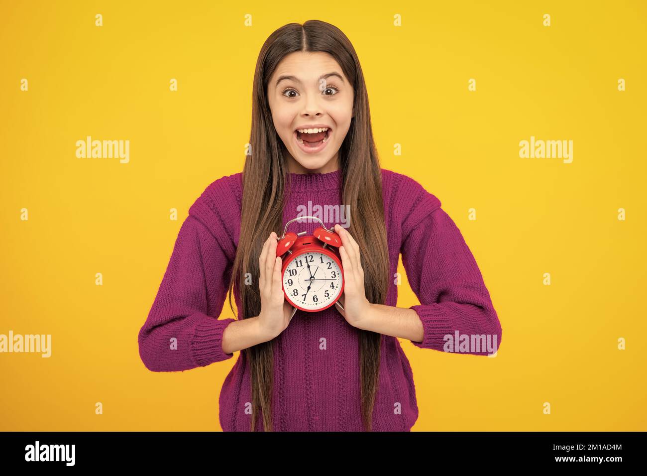 Excited face. Teen student girl hold clock isolated on yellow ...