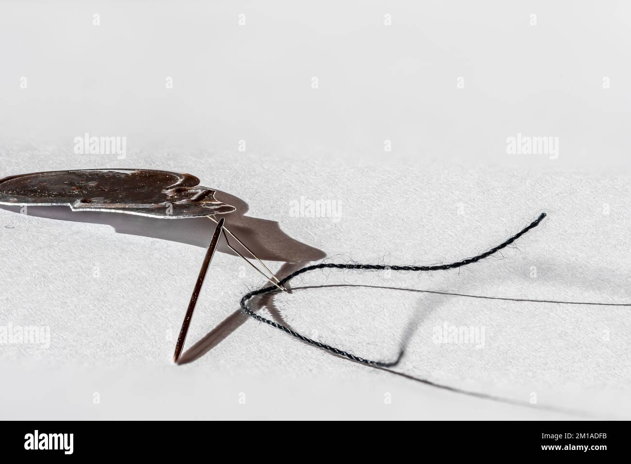 Sewing needle threader tool in use and a single black string Stock ...