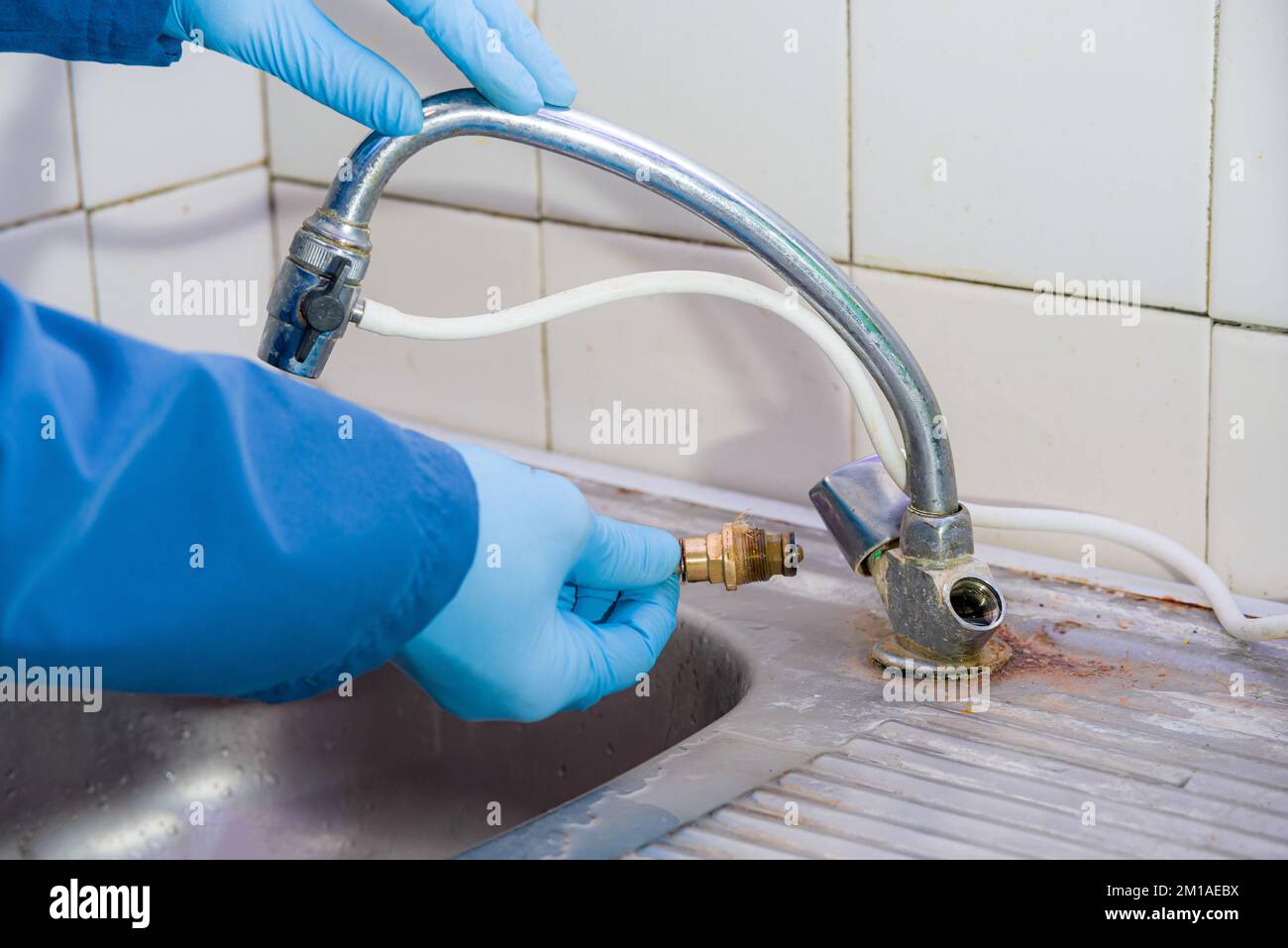 The plumber unscrews the valve from the tap. The master works in ...