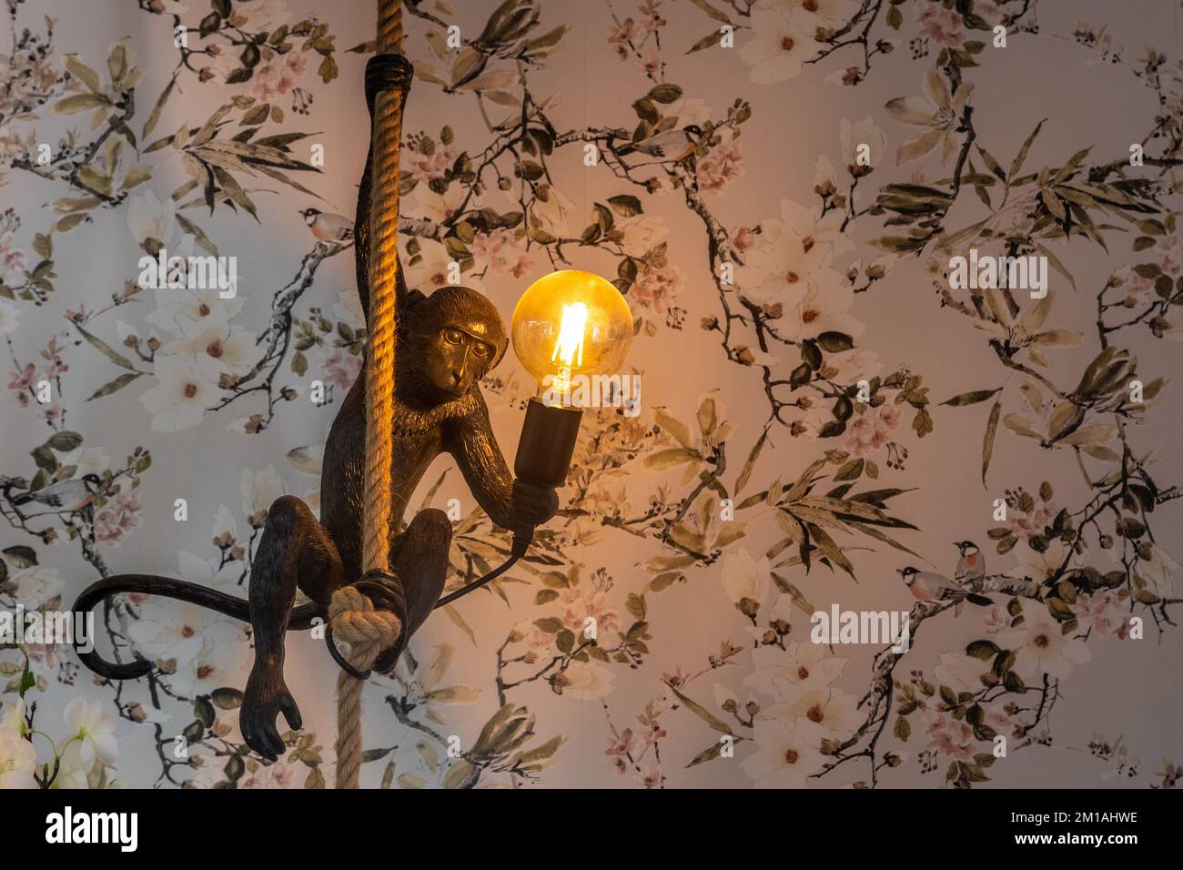 A cute monkey sculpture holding an illuminated electric lamp against ...