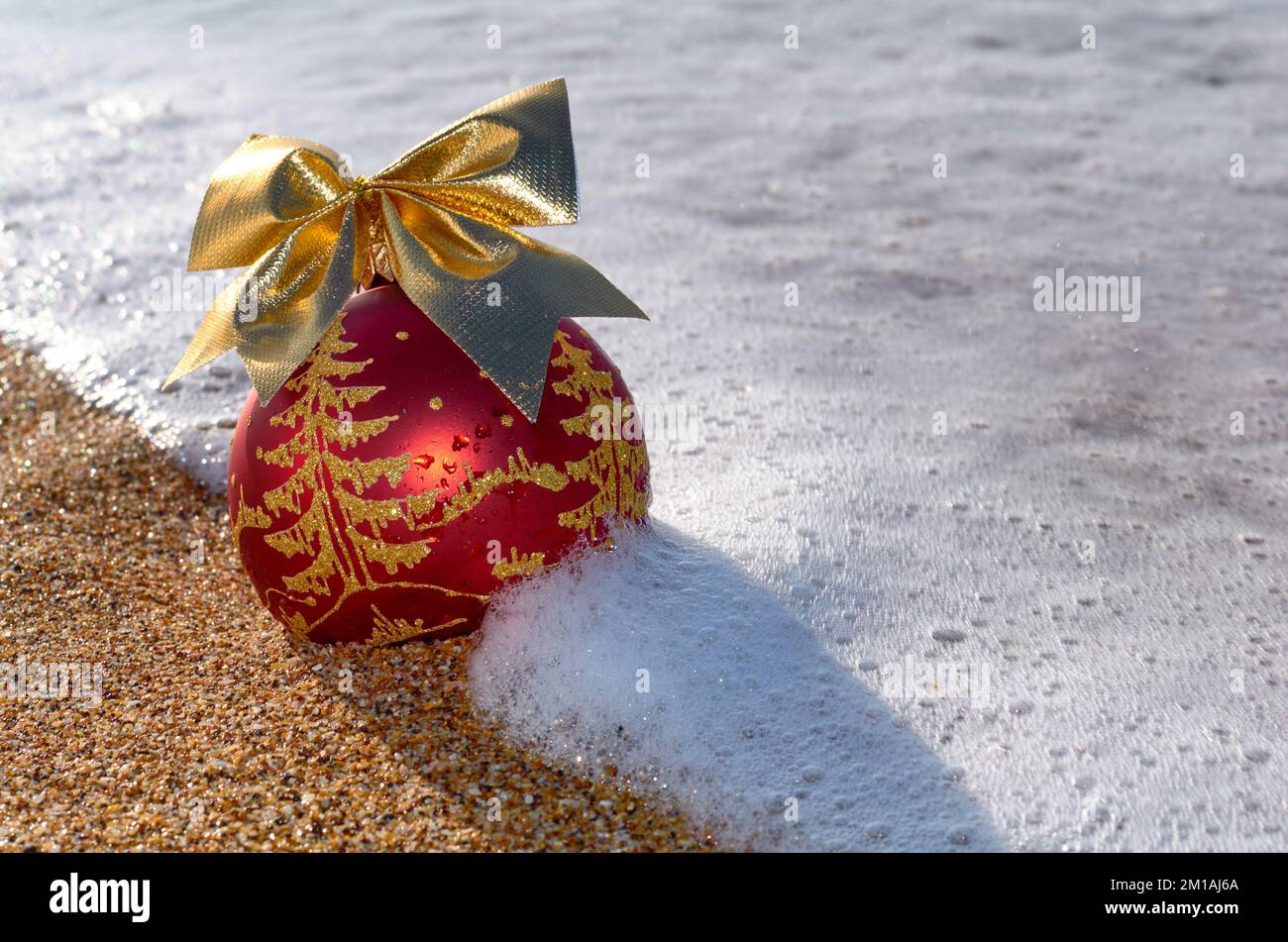 Christmas tree decoration on the beach sand in the foam of the sea wave ...