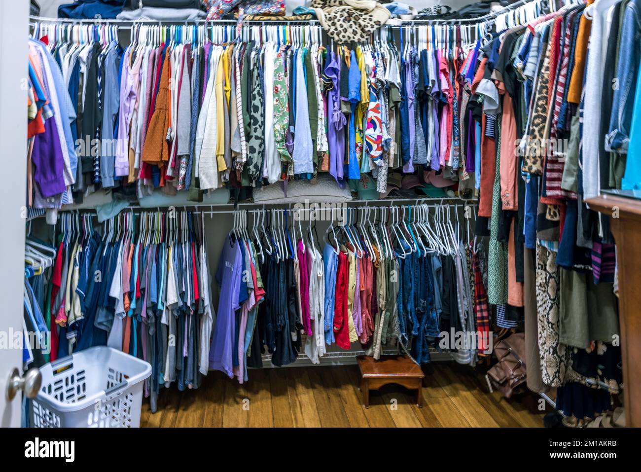 a very full and packed master bedroom closet of clothing with hanging ...