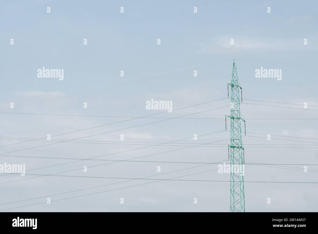 A high-voltage steel pylon tower with electric lines on a rural field ...