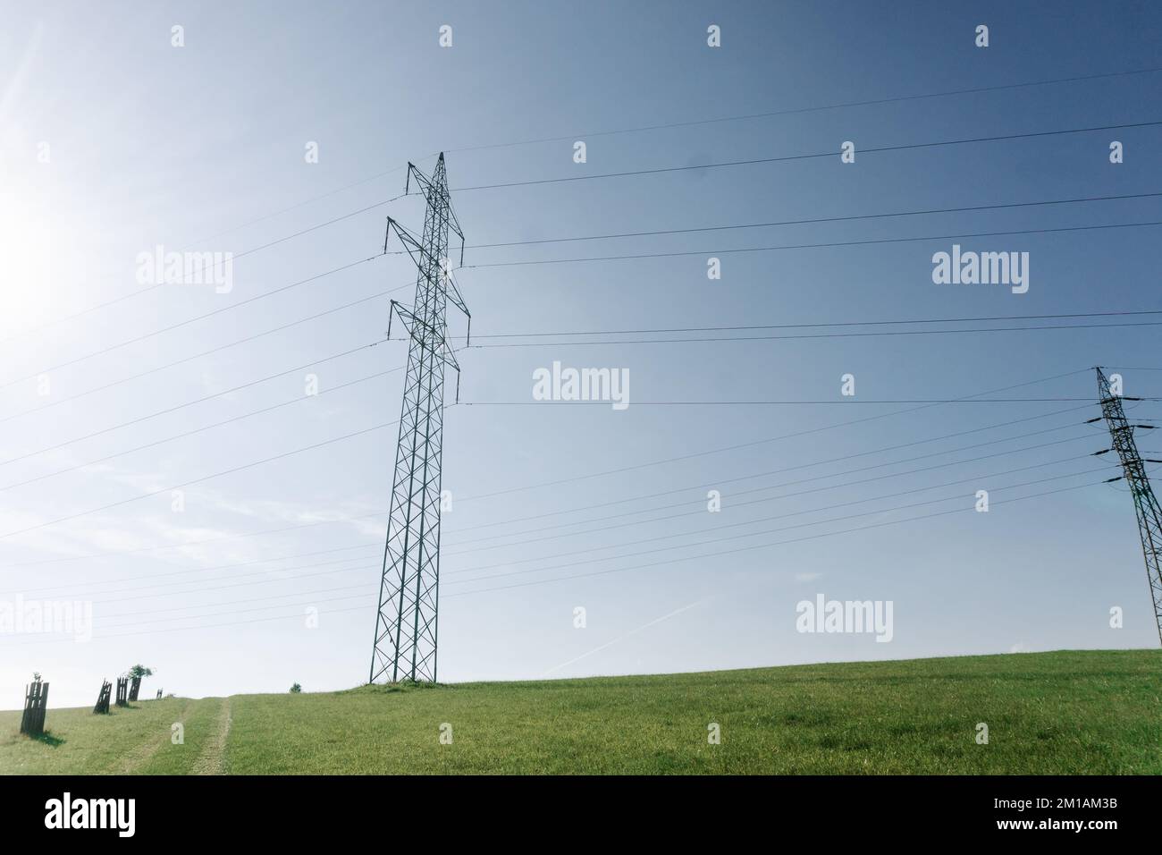 A high-voltage steel pylon tower with electric lines on a rural green ...