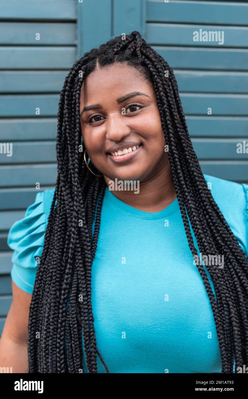 Portrait of a dark-skinned girl whose hair is braided against a blue ...