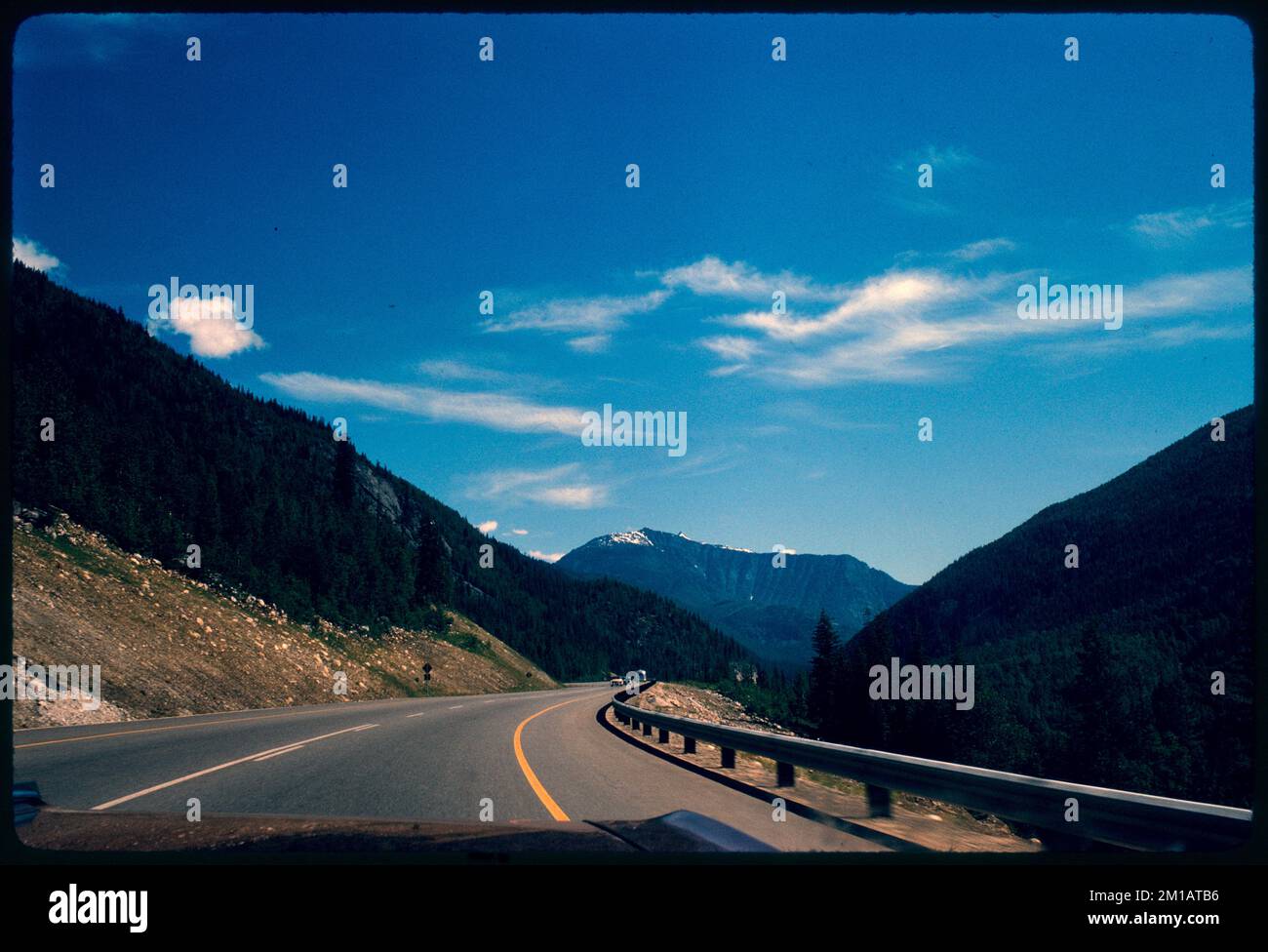 View down road between tree-covered mountain slopes, British Columbia ...