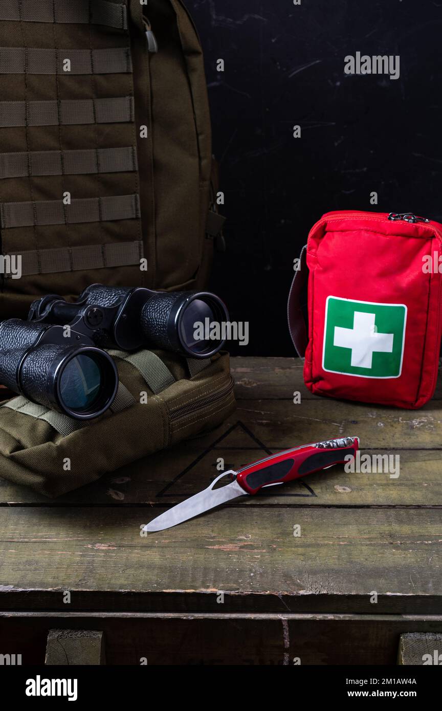 Swiss army knife and first aid kit. Binoculars and military backpack on ...