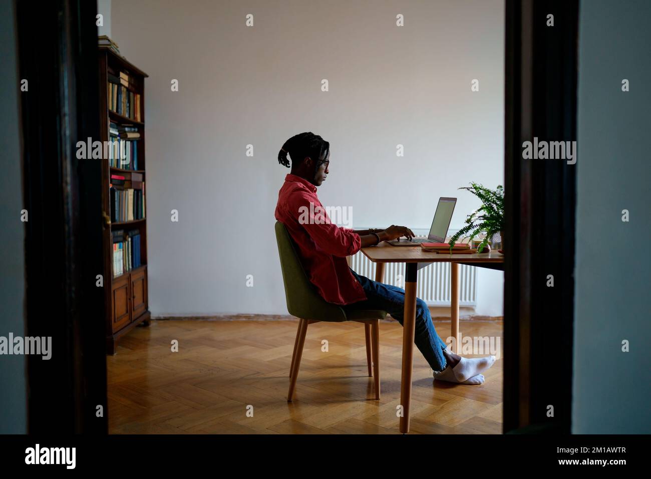 African self-employed guy freelance sits at desk using laptop working ...