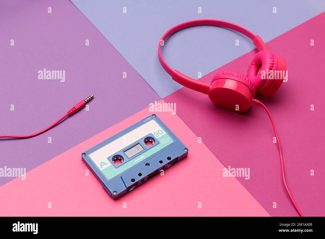 A-side of blue audio cassette and pink headphones on a color paper ...