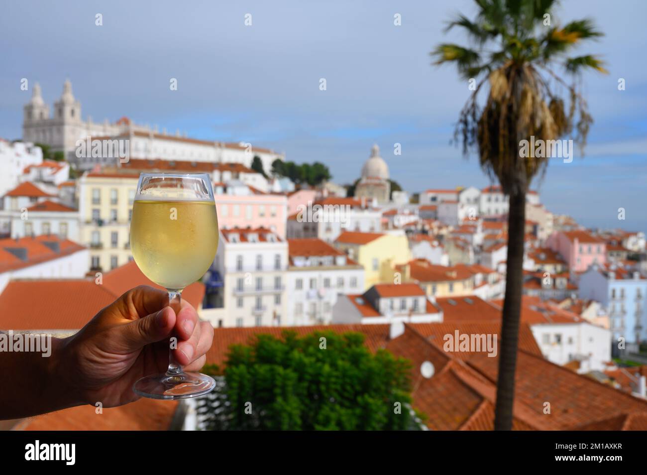 Hand with glass of cold white Portuguese wine in outdoor cafe at view ...