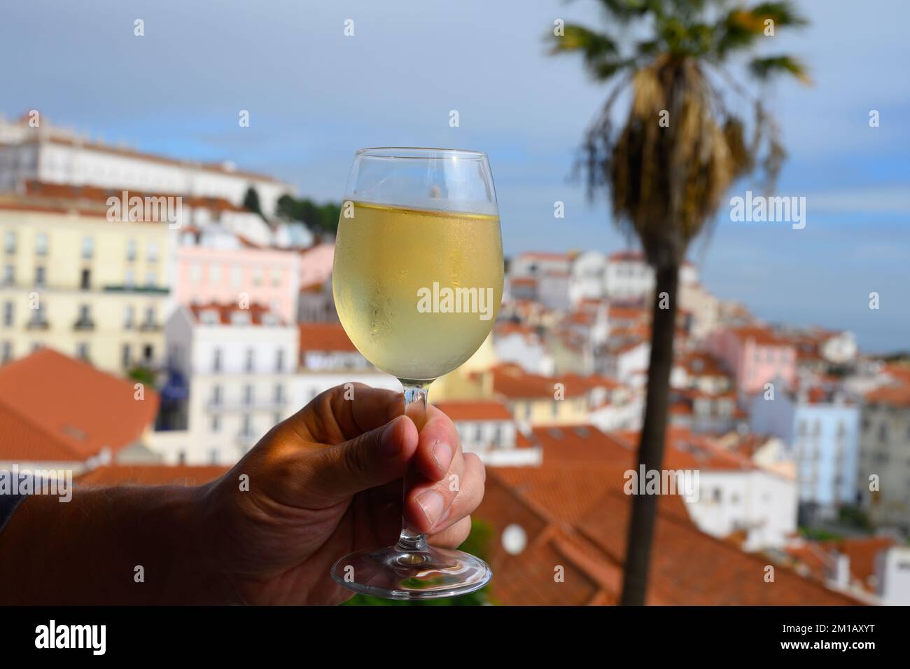 Hand with glass of cold white Portuguese wine in outdoor cafe at view ...