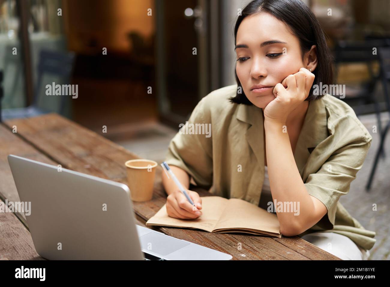 Portrait of young korean girl making notes, listening online meeting ...