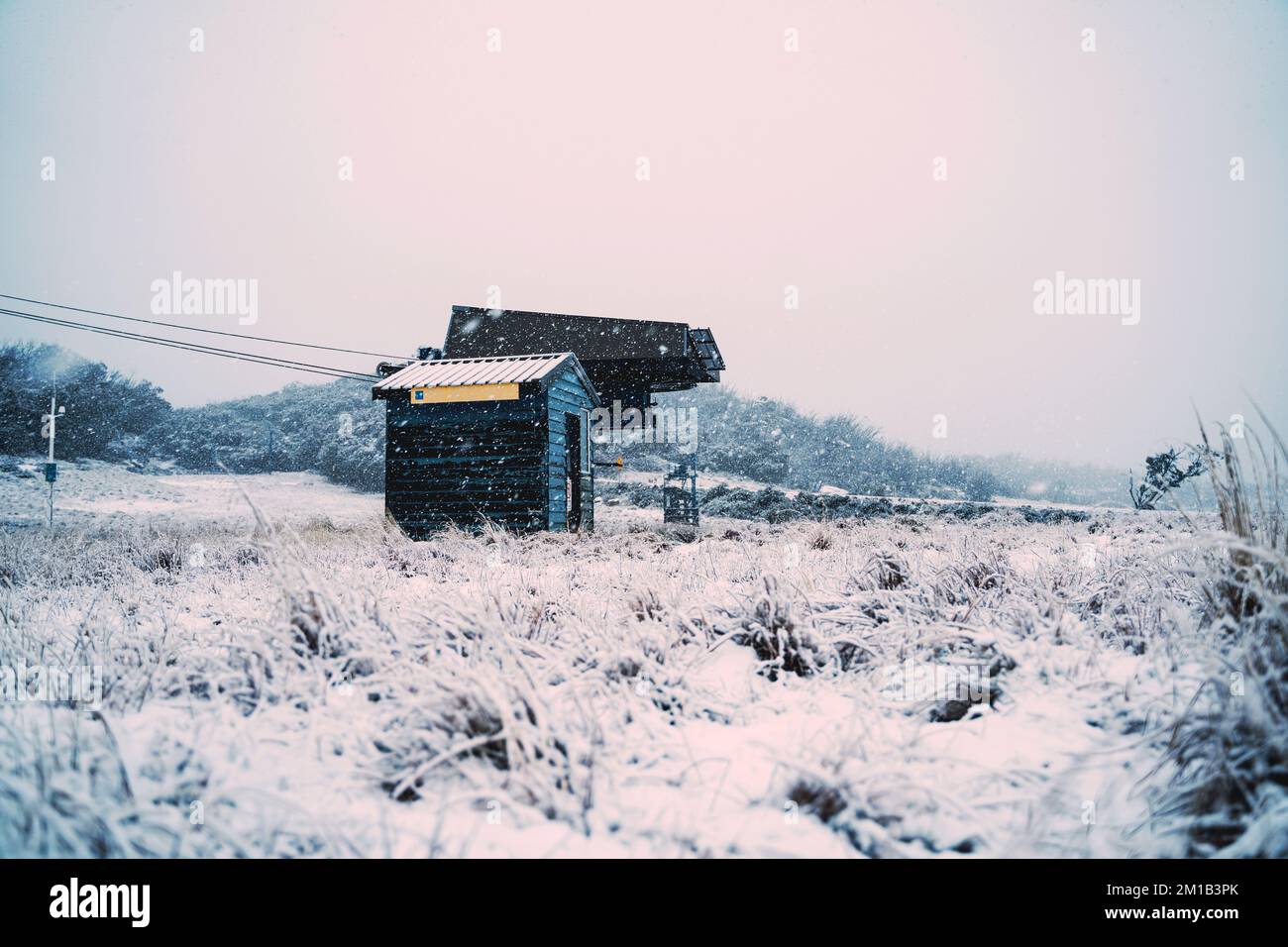 A winter landscape with a small lone house near the forest, power lines ...