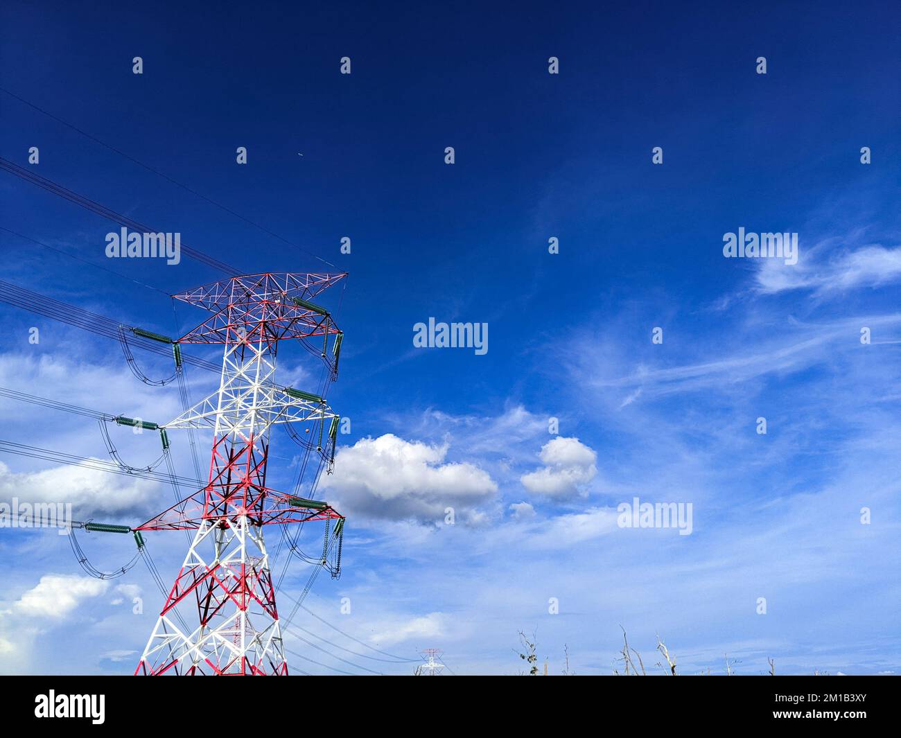 Red and white painted power pole with multiple high-voltage power lines ...
