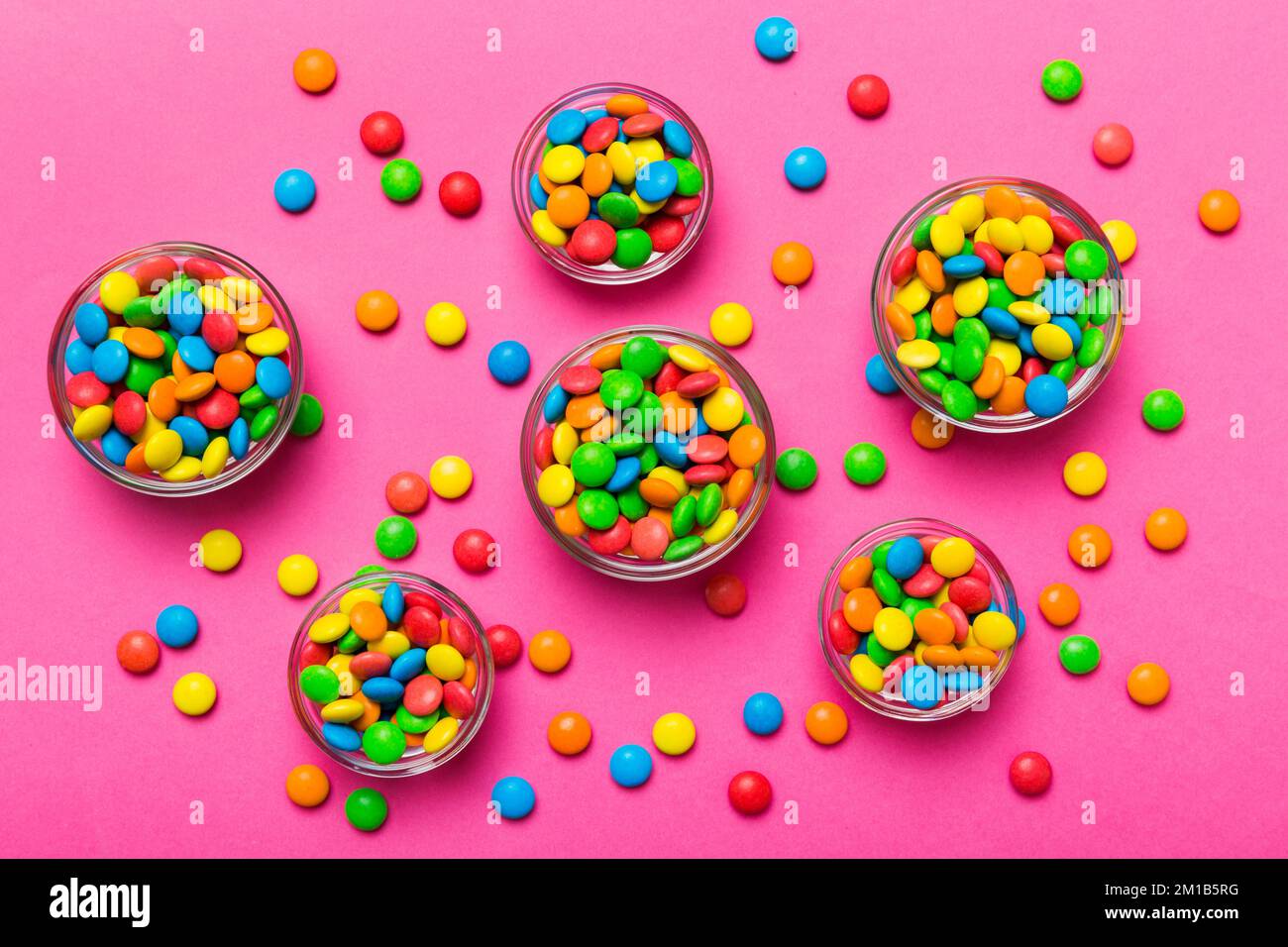 different colored round candy in bowl and jars. Top view of large ...
