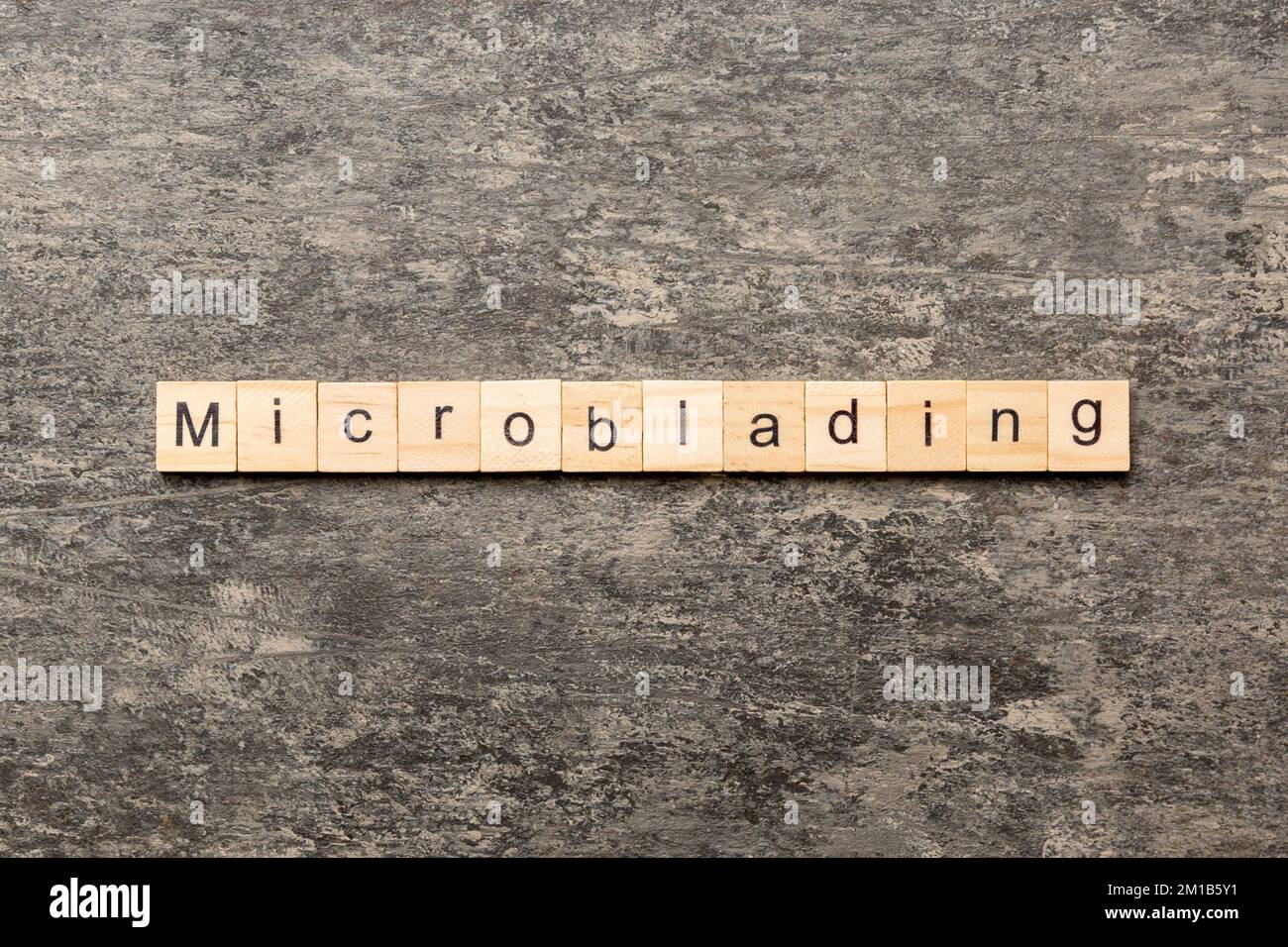 Microblading word written on wood block. Microblading text on cement ...