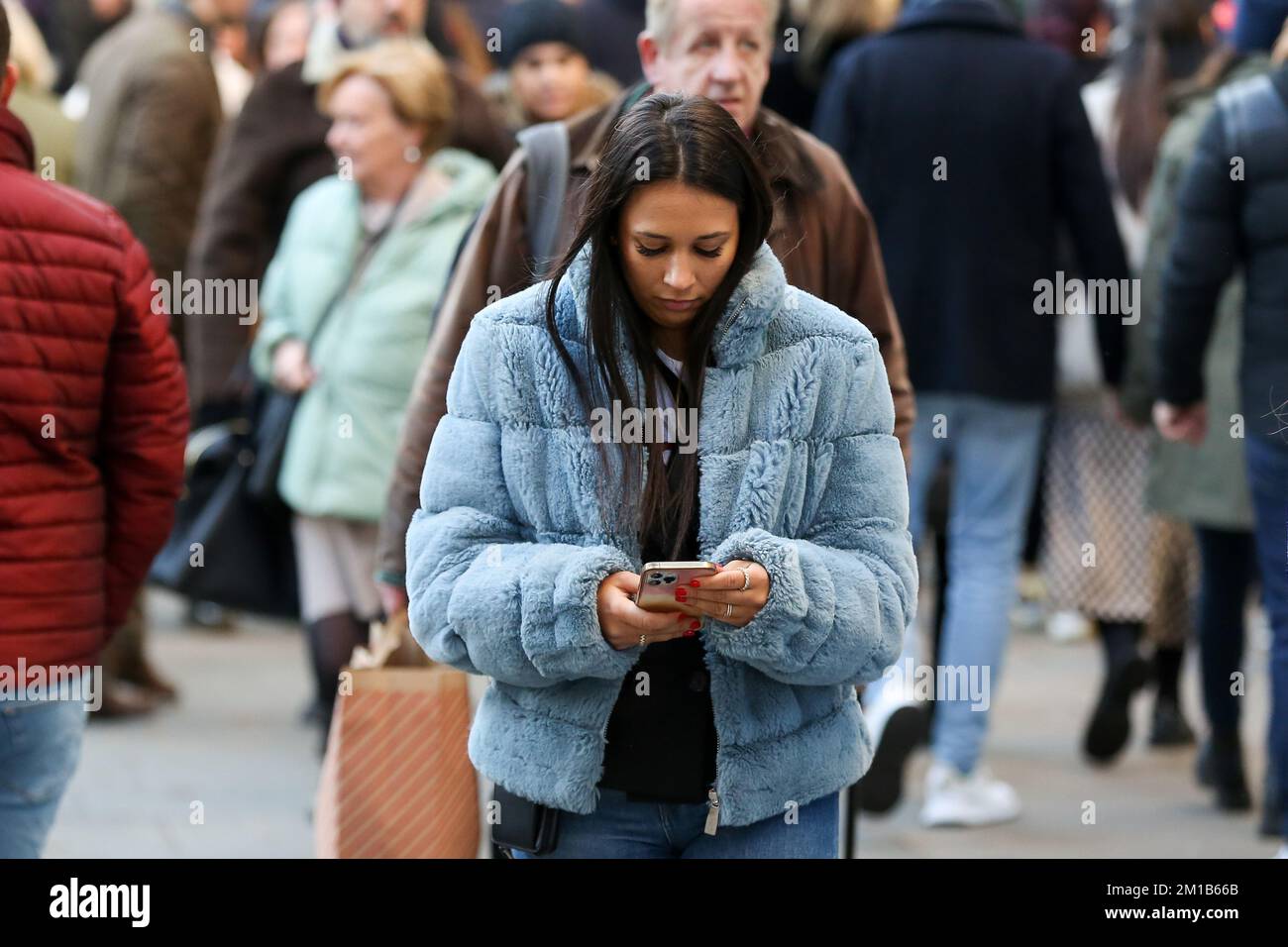 A woman uses her mobile phone while walking along Oxford Street in ...