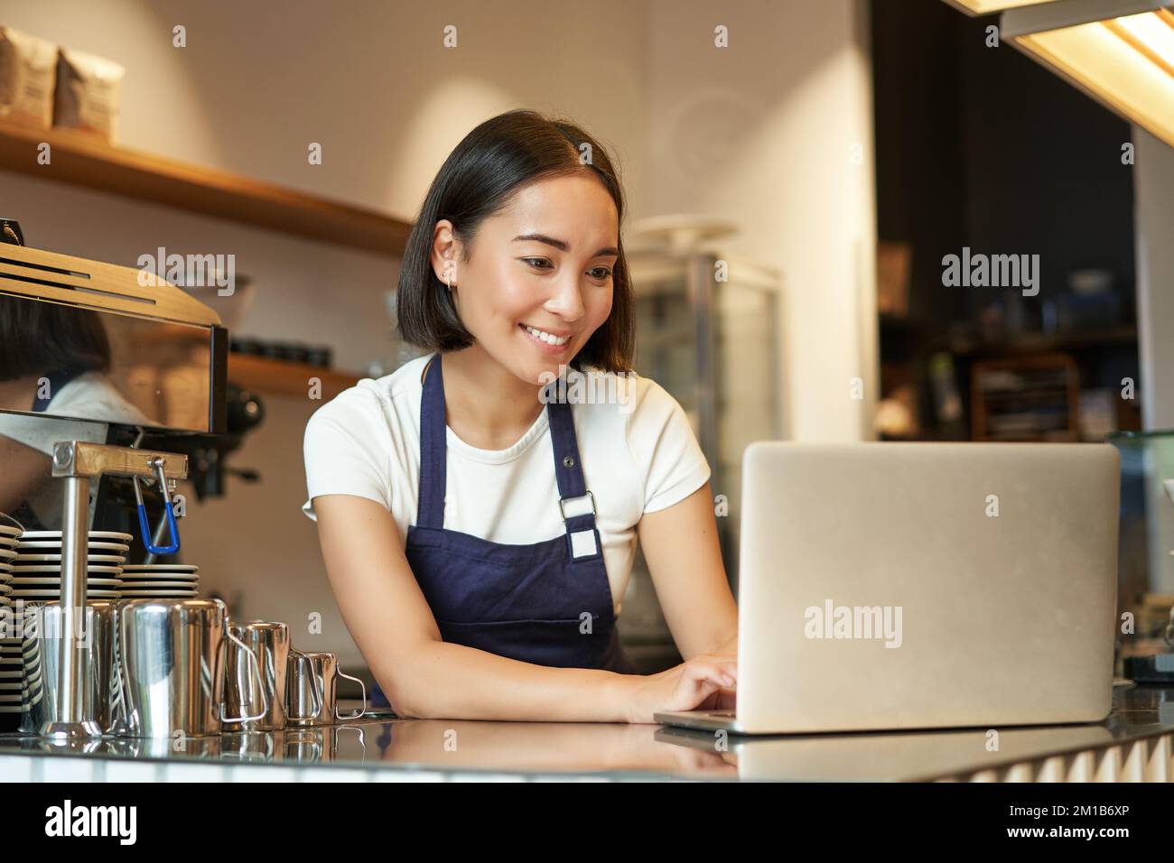 Portrait of smiling asian barista, cafe owner entrepreneur, working on ...