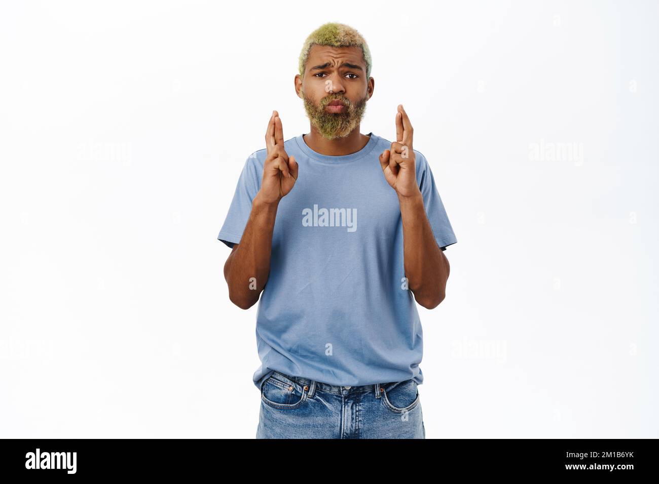 Hipster guy with yellow beard makes wish, holds fingers cross, praying ...