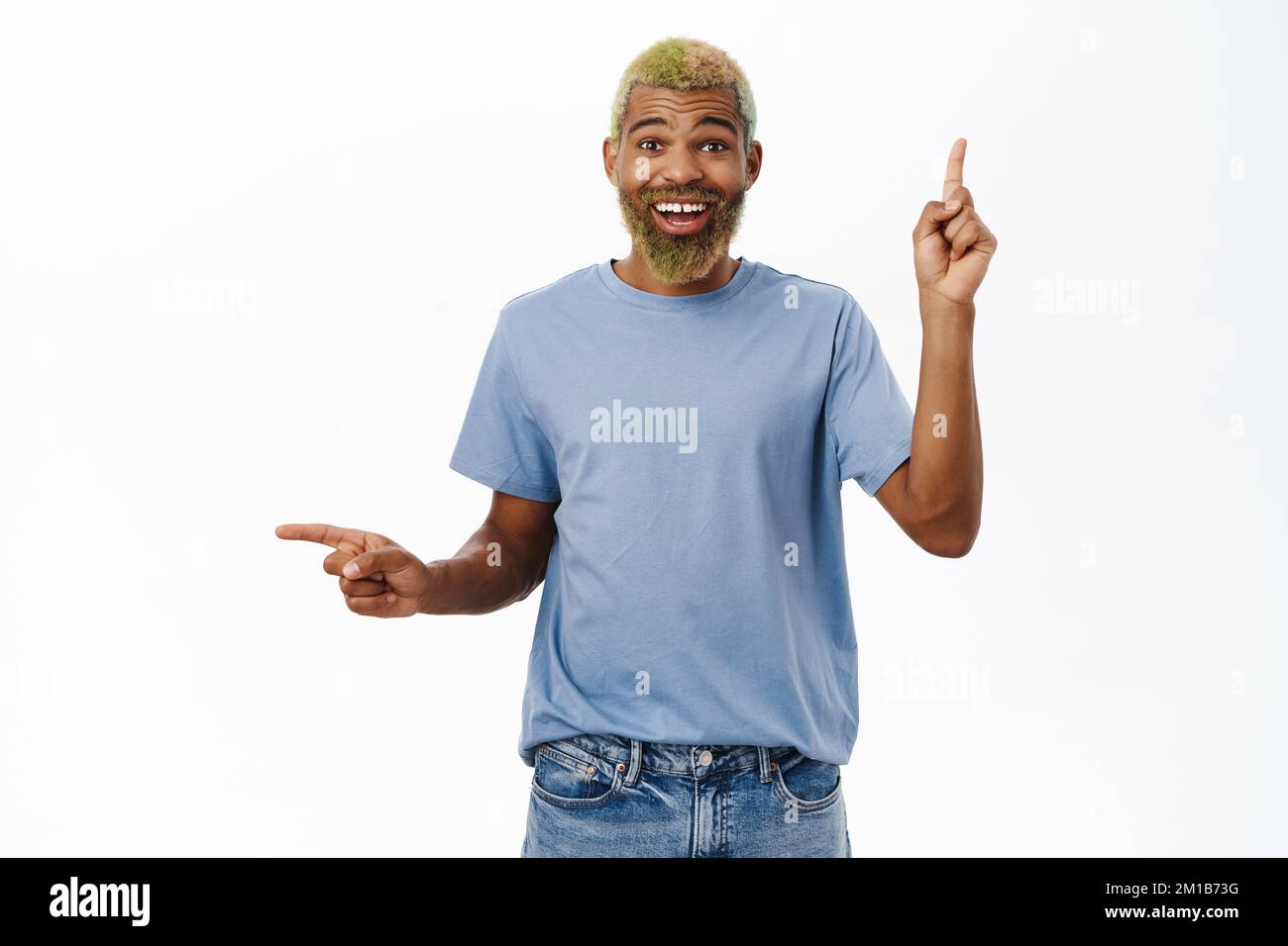 Handsome hipster guy points at left and top side, shows advertisement ...