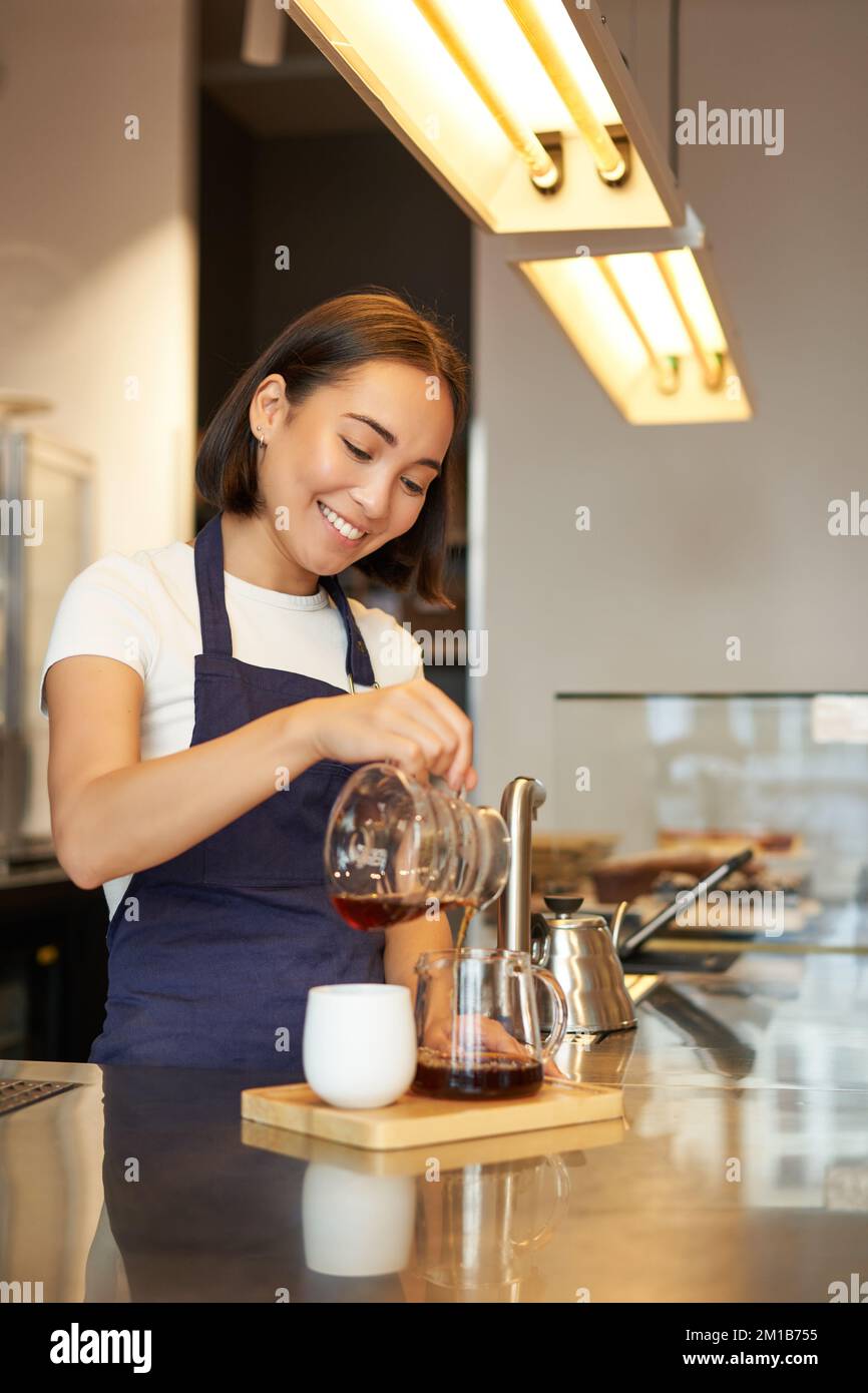 Cute korean barista girl, pouring coffee, prepare filter batch brew ...