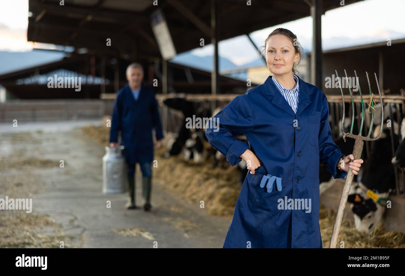 Confident female livestock farm worker with pitchfork in outdoor ...
