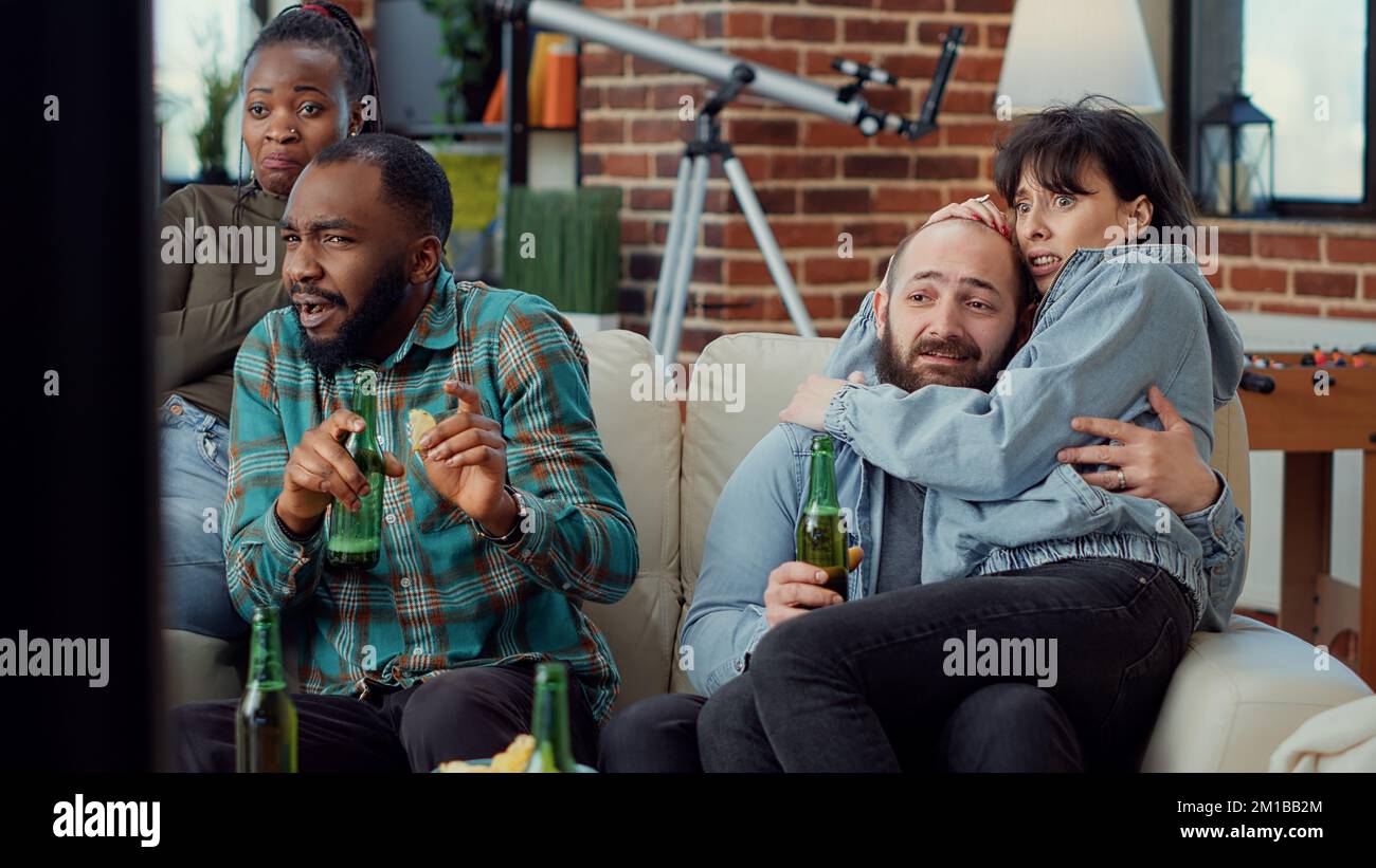 Terrified people being afraid of scary film on television, having ...