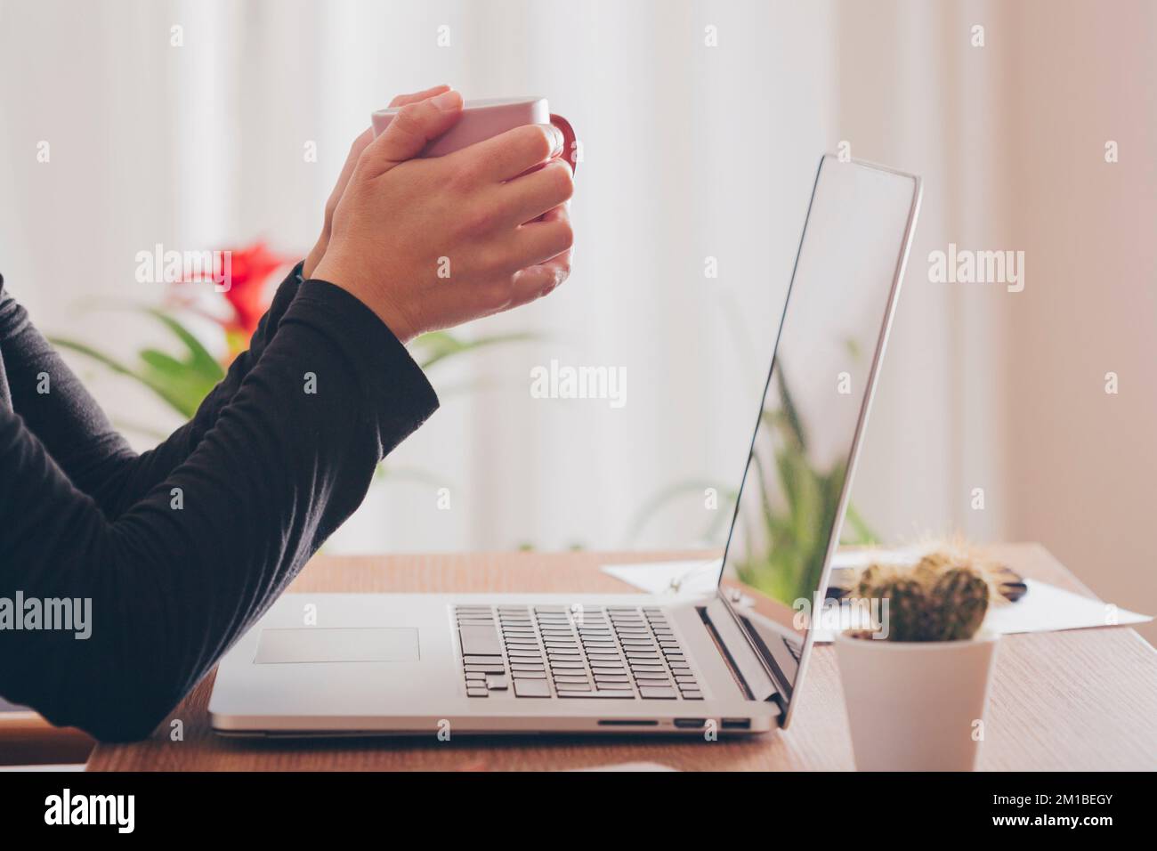 Woman with cup of coffee on her desk. Drinking coffee while looking at ...