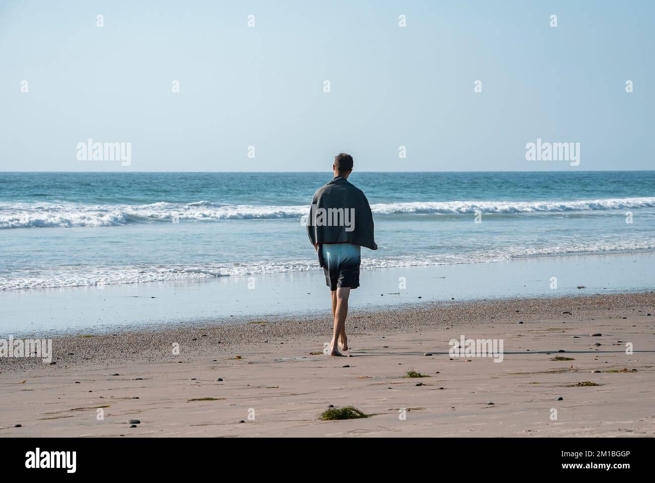Rear view of man with towel walking at beach in summer Stock Photo - Alamy