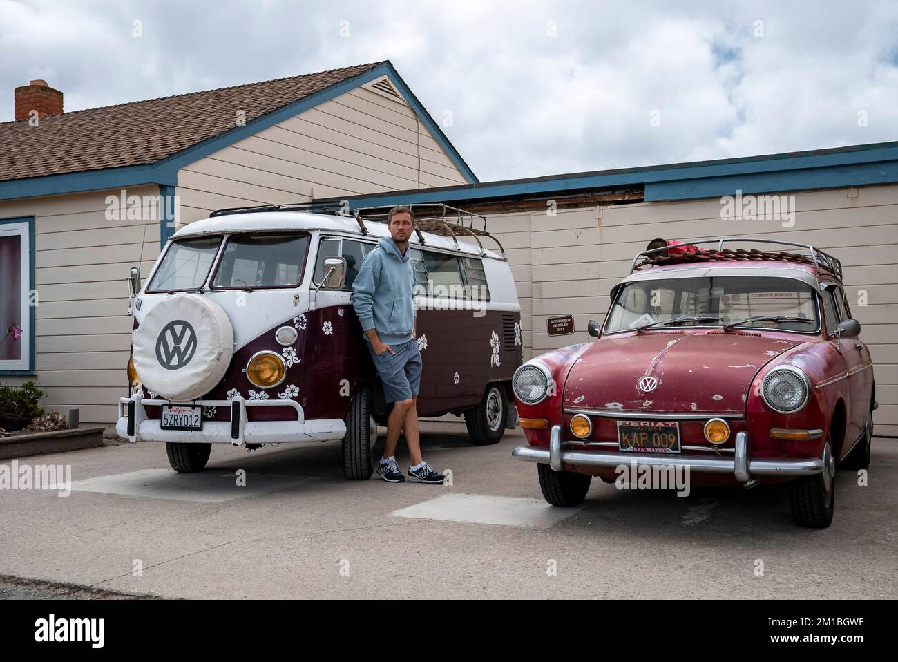 Young man standing by vintage classic VW Camper Van parked on Seafront ...