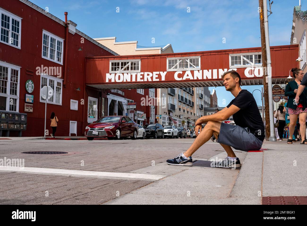 Thoughtful man sitting on sidewalk with Monterey Canning Company in ...