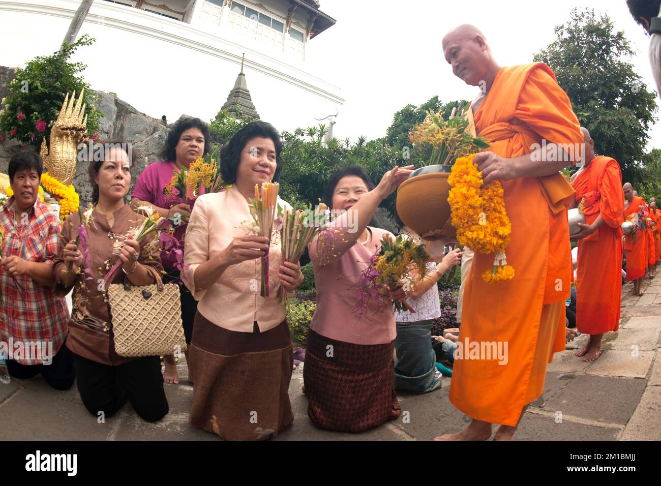 Group of monks receiving flower offering from people in Tak Bat Dok Mai ...