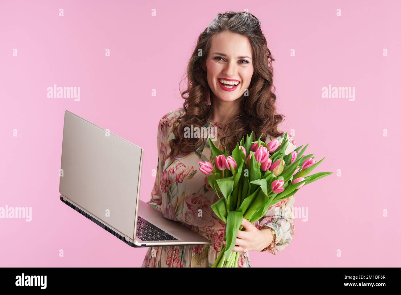 smiling modern middle aged woman in floral dress with tulips bouquet ...