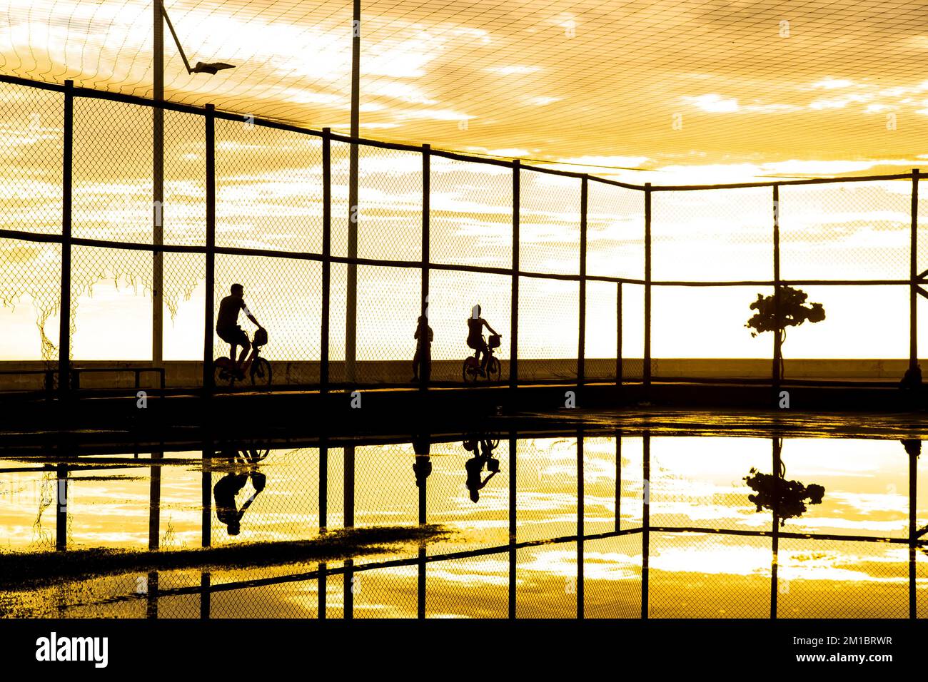 Cyclist exercising on the edge of Rio Vermelho beach against sunset ...