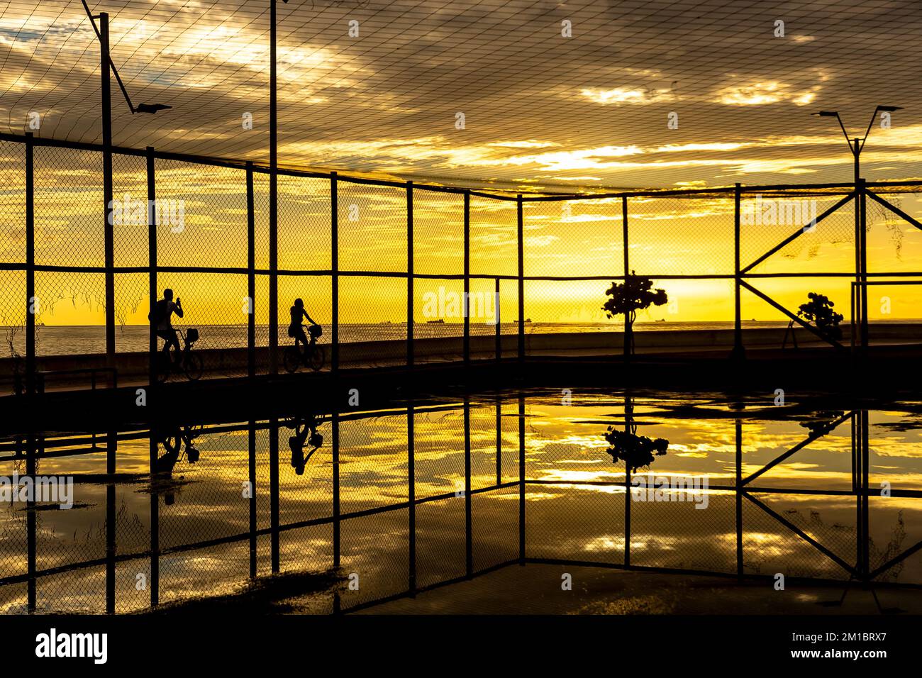 Silhouette of people at sunset exercising on the edge of Rio Vermelho ...