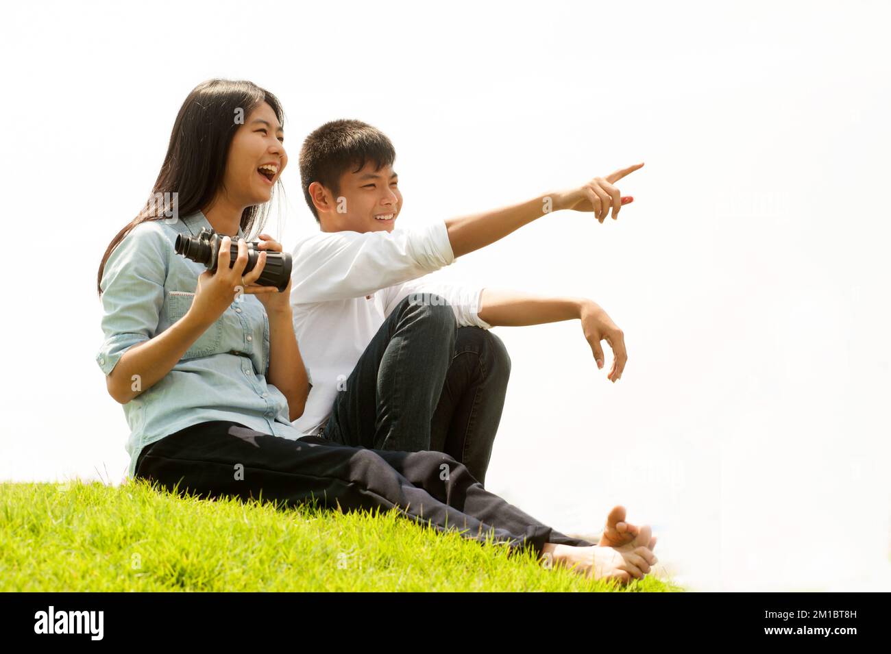 Asian young boy and girl sit on mound seeking Binoculars Stock Photo ...