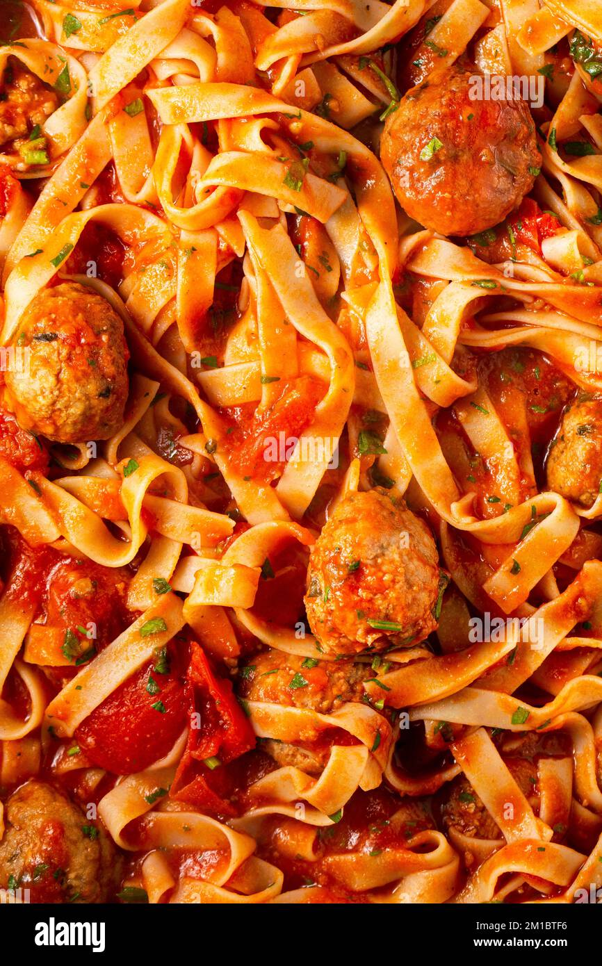 Texture of pasta in tomato sauce with meatballs as a background. A ...