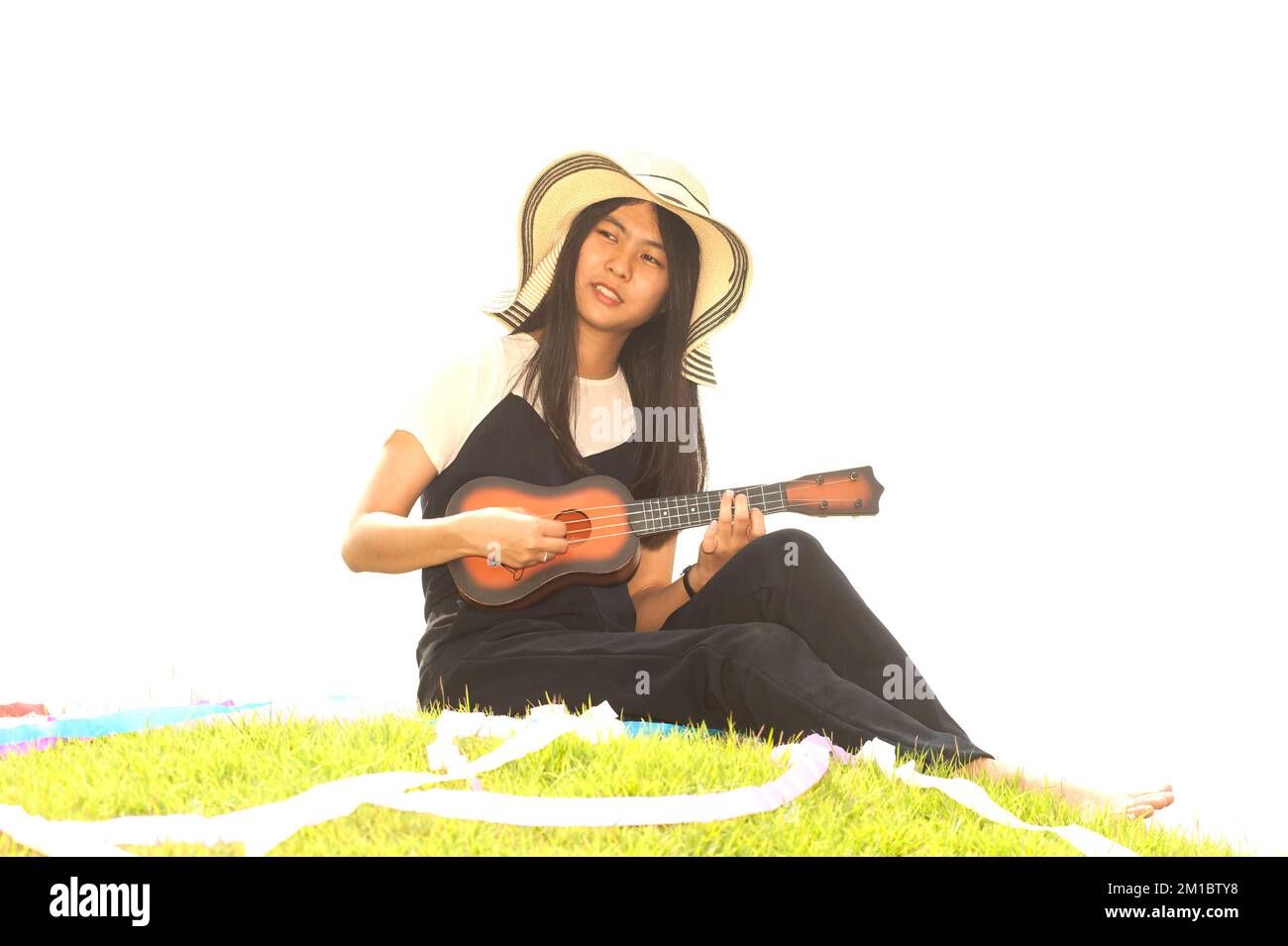 Pretty Asian young woman sit on mound playing Ukulele Stock Photo - Alamy