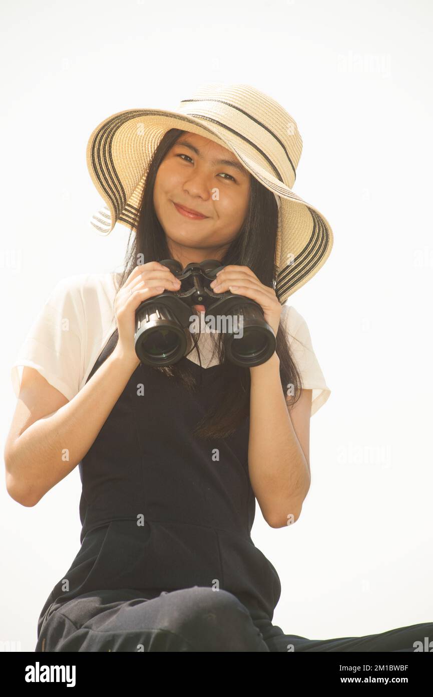 Pretty Asian young woman sit on mound seeking binoculars Stock Photo ...